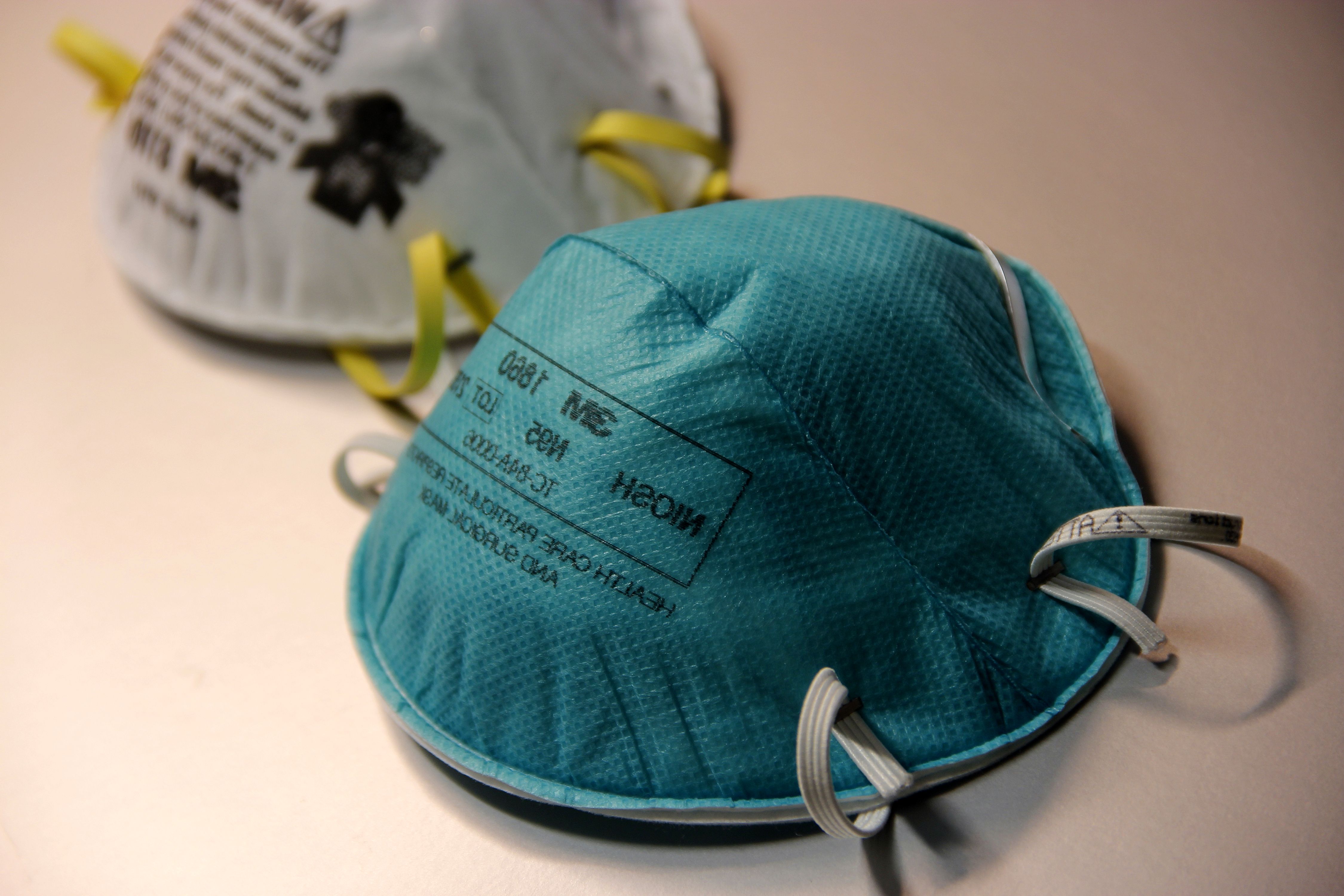 N95 type masks lying atop of a silver table top one turquoise in - AgroWeb